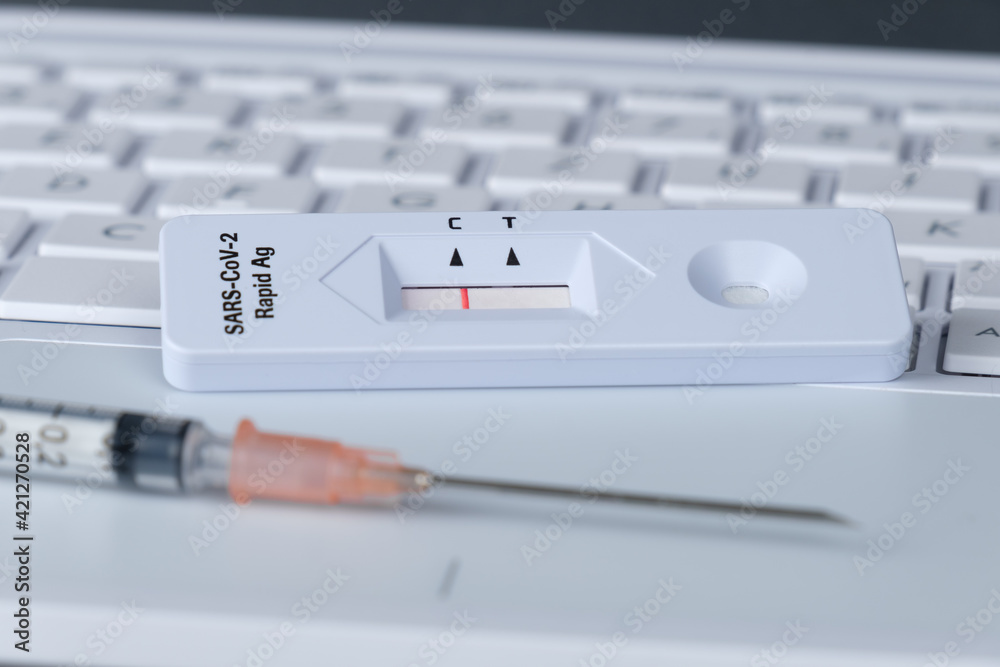 Antigen Schnelltest COVID-19 und eine Spritze Injektionsnadel zum ...