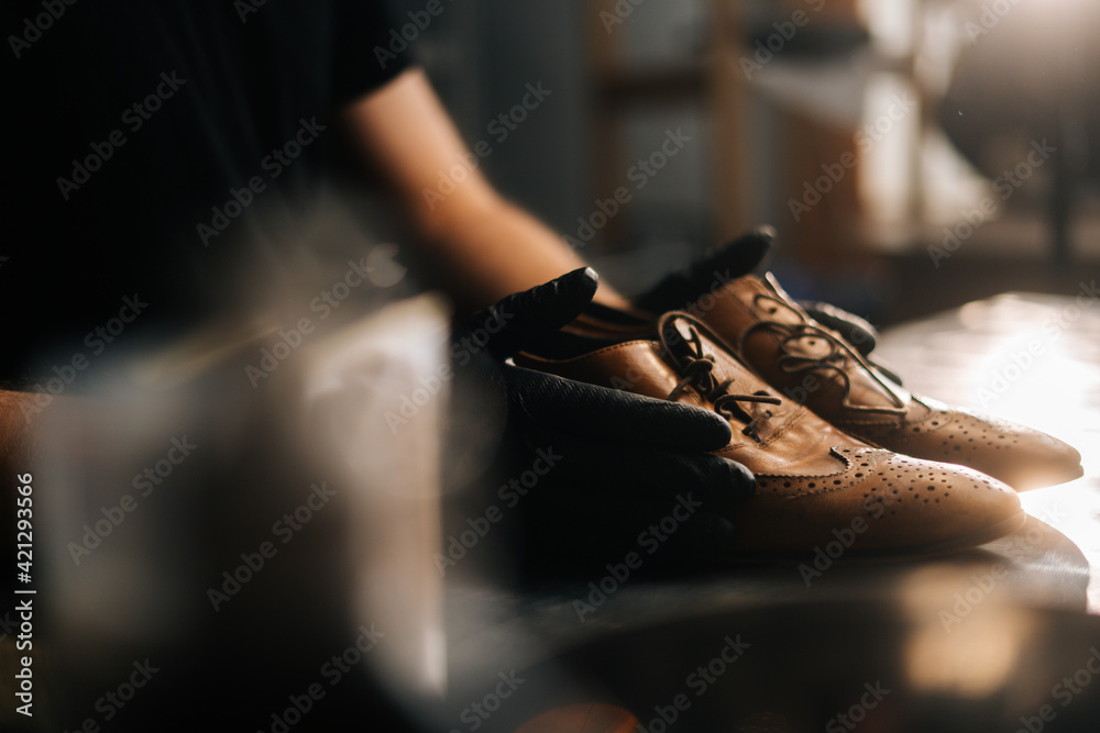 Close-up side view of hands of shoemaker shoemaker in black gloves ...