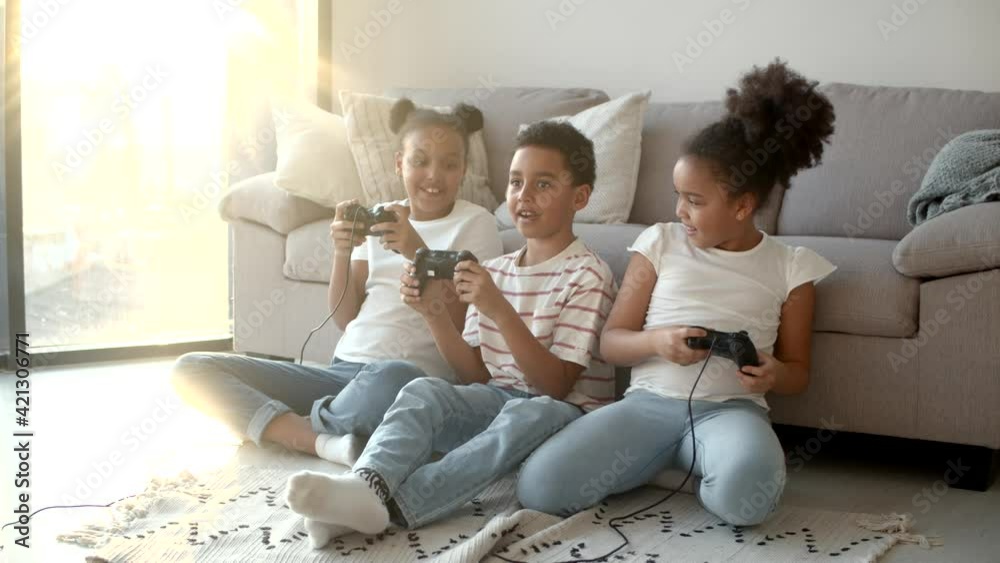 Happy african american kids playing video game with joystick at home ...