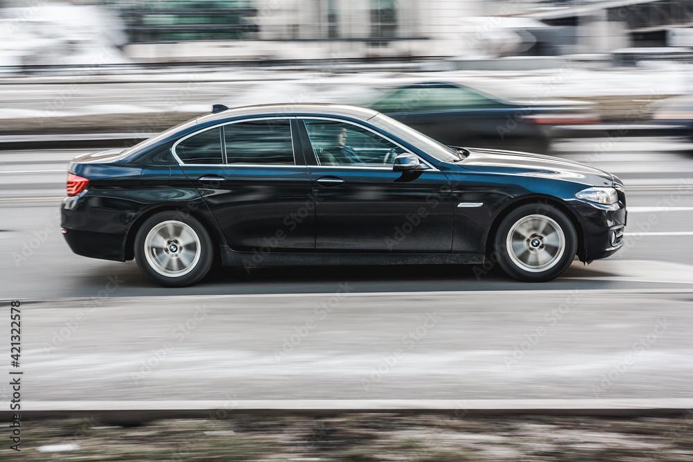 BMW 5 series on the road in motion. Fast speed drive on city road. Side ...