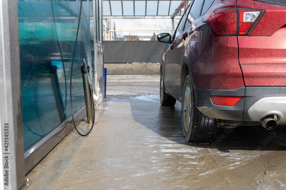 washing car at autowash . Car wash. red machine under the pressure of ...