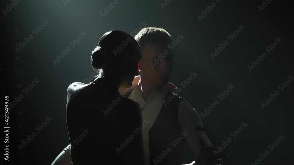 Couple is dancing fast rhythmic tango dance in dark studio with bright ...