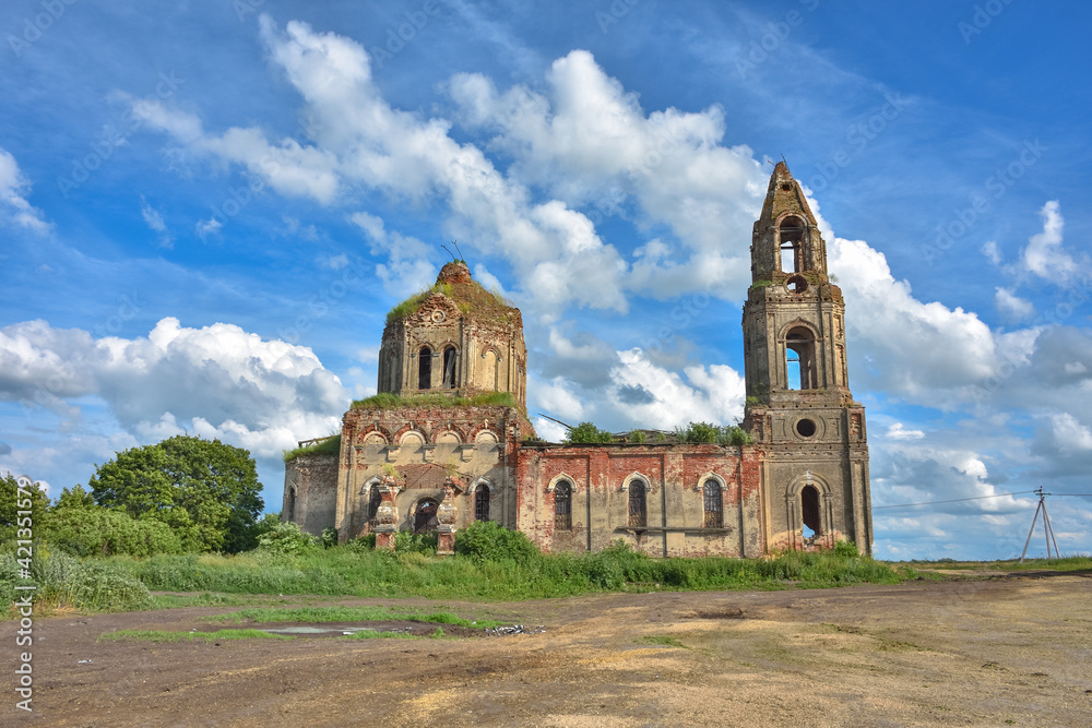 ruined church with a bell tower overgrown with grass against a cloudy ...