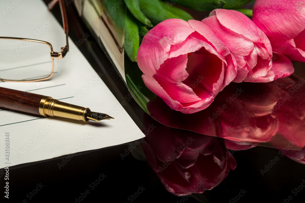Stylish pen on a blank sheet of paper and flowers in transparent ...