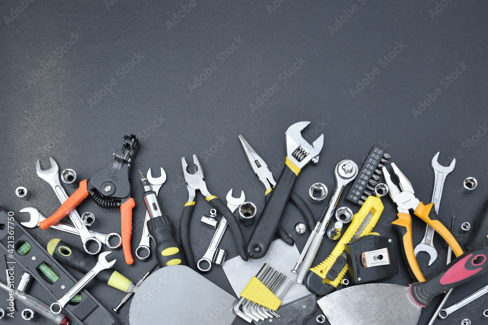 Handyman tool kit on black wooden table. Many wrenches and screwdrivers ...