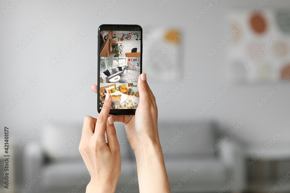 Woman with mobile phone looking at the images of cctv cameras installed ...