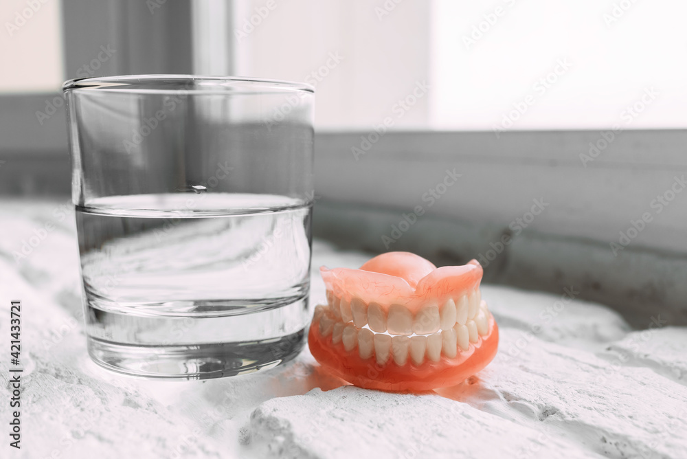 A denture in a glass of water. Dental prosthesis care. Full removable ...