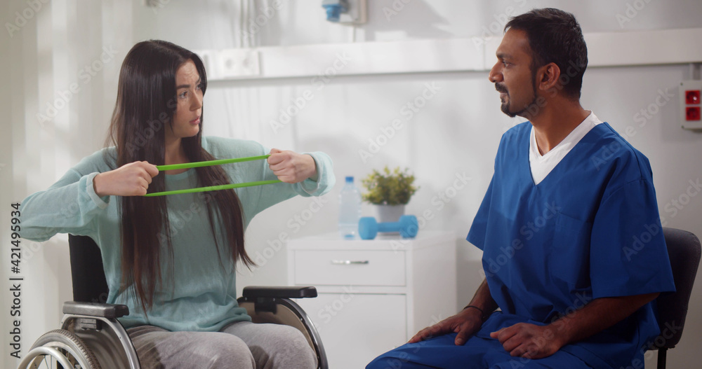 Disabled young female patient in wheelchair during rehabilitation with ...