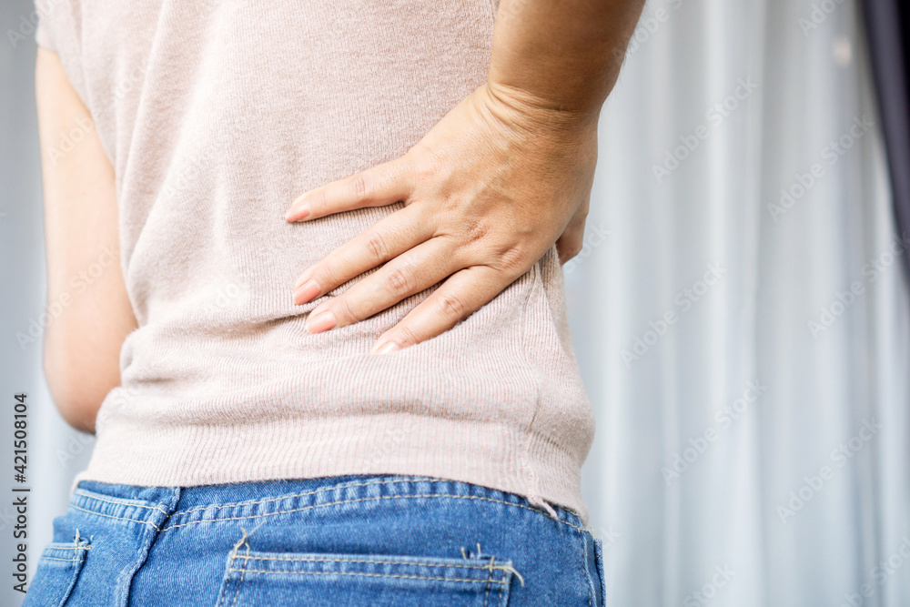 woman suffering from lower back pain, hand holding right side back pain ...
