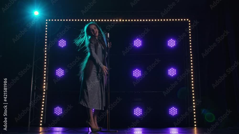 Bottom view of female vocalist singing on stage in dark against ...