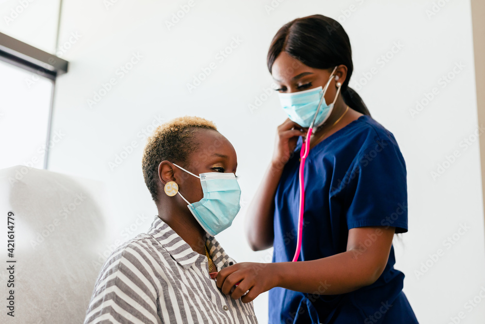 Black nurse takes vitals of black female patient in exam room at ...