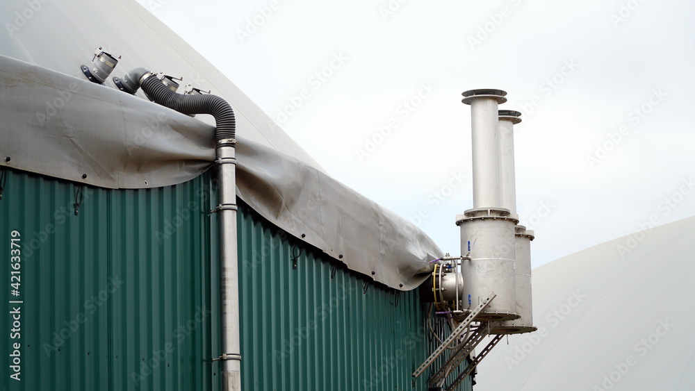 Biogas. Aerial view of a biogas plant and a farm in green fields. Renewable energy from biomass ...