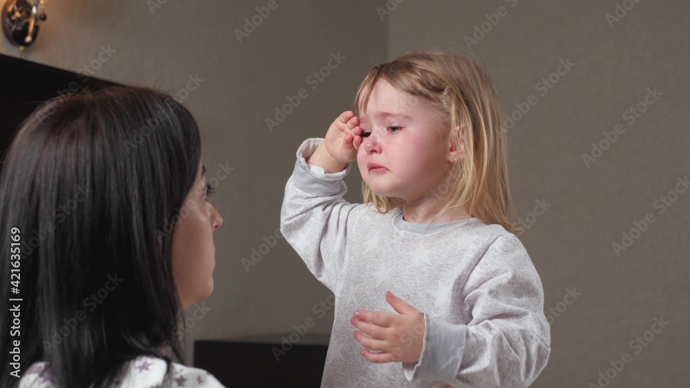 Child is crying in room in the arms of his mother. Mom calms child ...