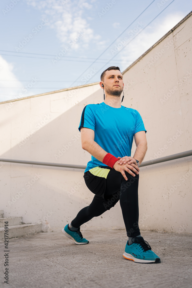 Young man runner getting ready to run stretching legs warm up quad ...