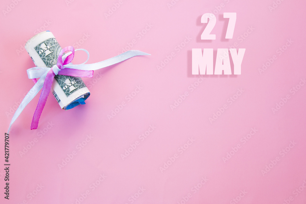 calendar date on pink background with rolled up dollar bills pinned by ...