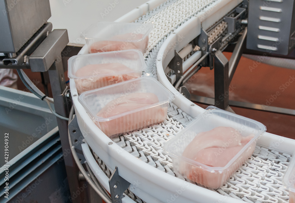 Food products meat chicken in plastic packaging on the conveyor.Factory ...