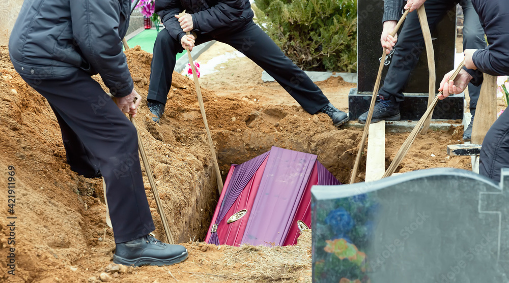 Burial. Men lower the coffin into the grave Stock Photo | Adobe Stock