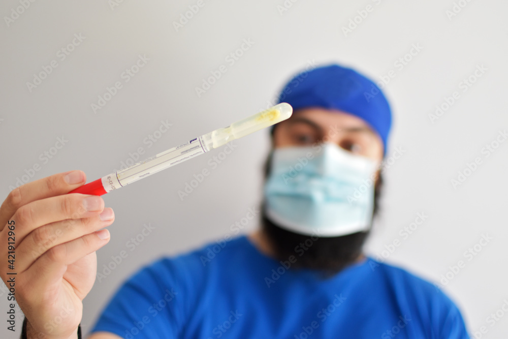 Nurse holding a tube. Rotavirus test. Man wearing a face mask grabbing ...