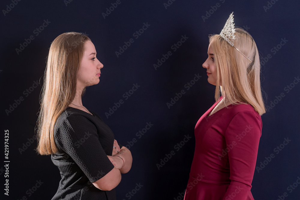 Two young girls, one with a crown on her head, stand opposite each ...