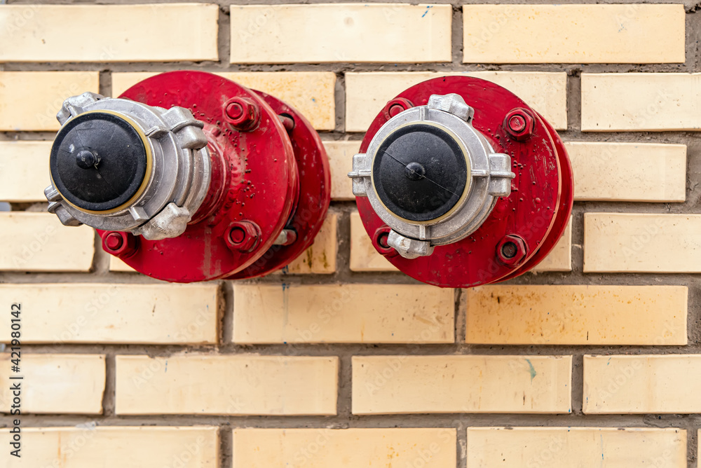 Double fire hydrant on the yellow brick wall. Stock Photo | Adobe Stock