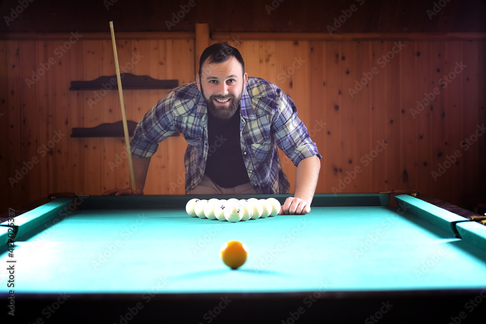 A man with a beard plays a big billiard. Party in a 12-foot pool ...