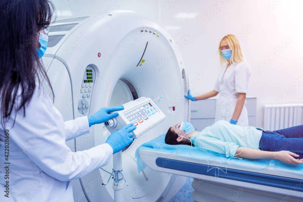 Radiologist with a female patient in the room of computed tomography ...