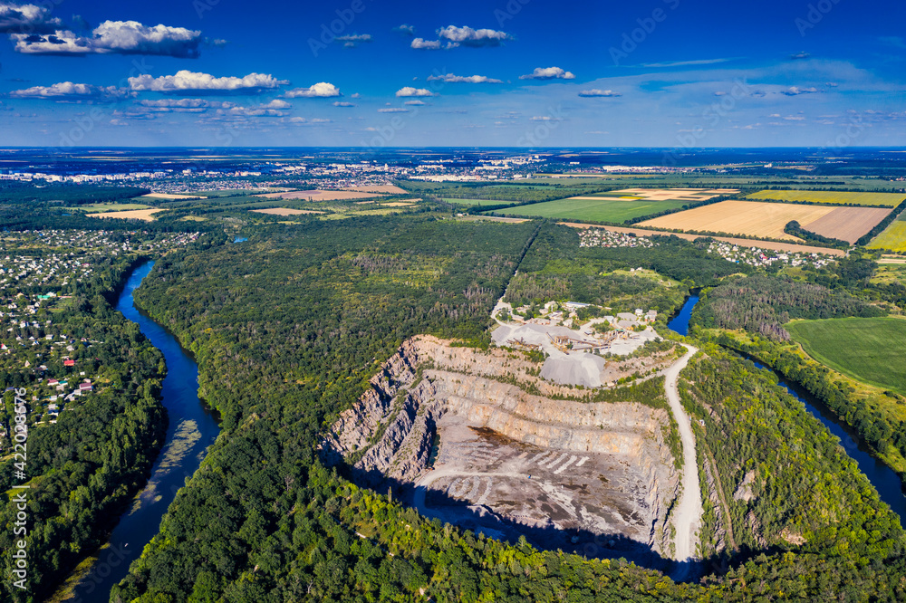 Top view of a stone, granite quarry. Beautiful forest, blue sky, clouds ...