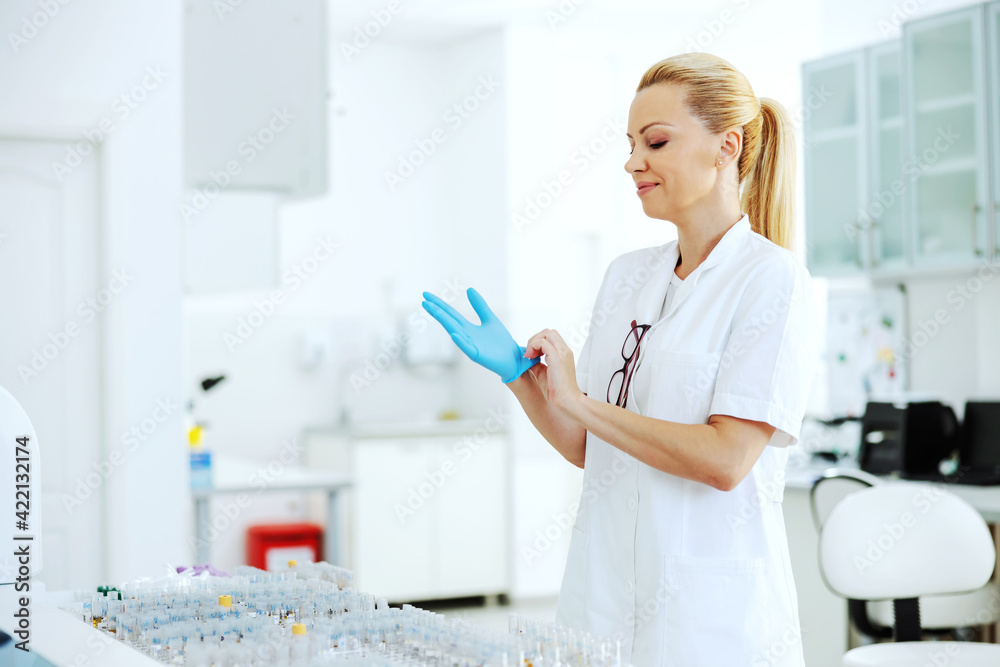 Middle aged attractive lab assistant in sterile white uniform standing ...