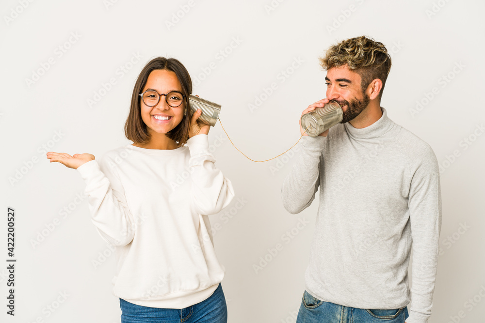 Young hispanic friends talking through a tin can system showing a copy ...