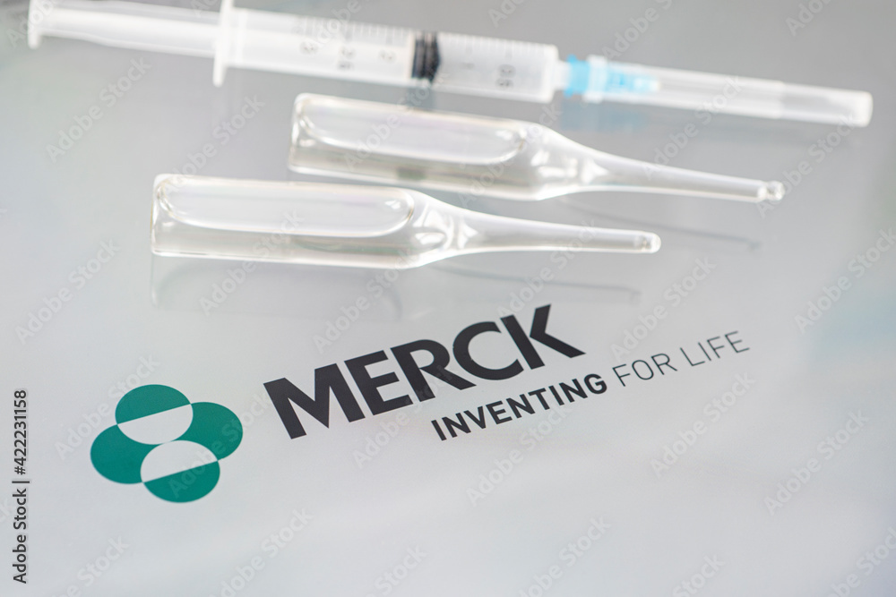 Vials of liquid on a white table and the logo of a large pharmaceutical ...