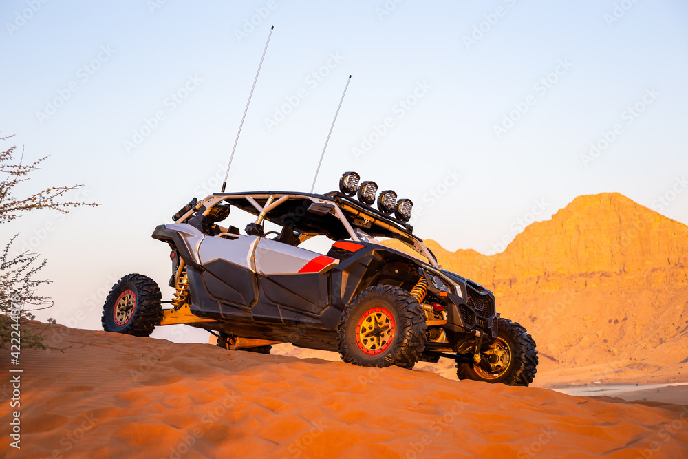 Modern dune buggy parked on sand in the desert with mountains in the ...
