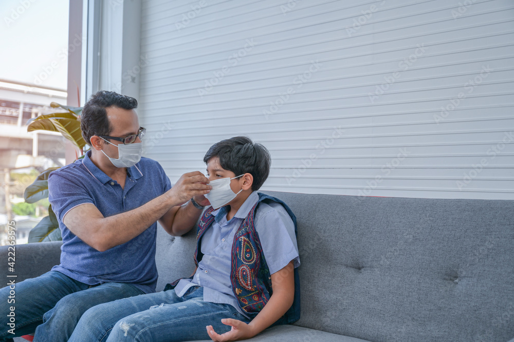 Foto de Indian father help his son wearing medical mask to protect ...