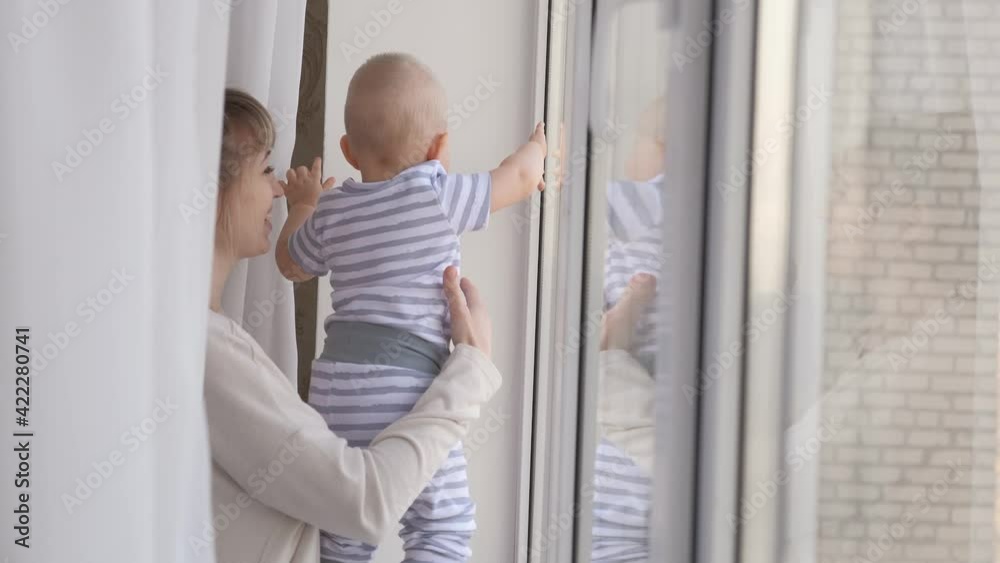 Mother, child, daughter are playing and looking out window at street ...