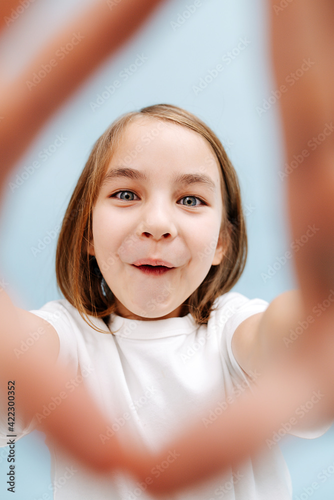 Funny smiling 9 year old girl through a finger frame she makes. Over ...