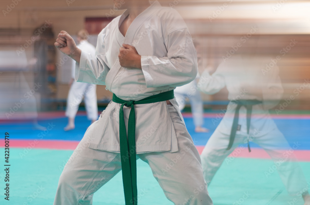 Karate-do training for teenagers. An athlete in a white kimano with a ...