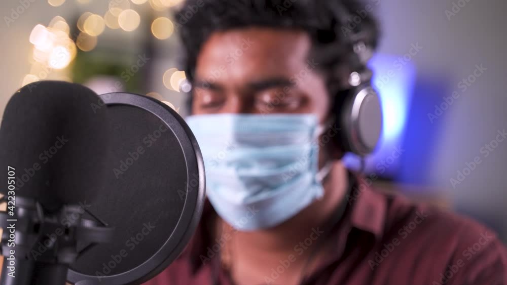 Pan shot rack focus of vlogger with medical face mask speaking in front ...