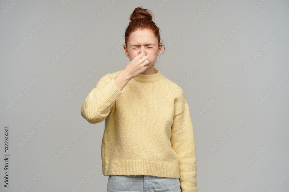 Portrait of sneezing, adult girl with ginger hair bun. Wearing yellow ...