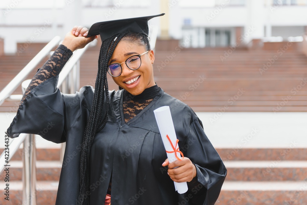 pretty african college student in graduation cap and gown in front of ...