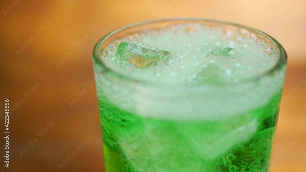 Air bubbles inside glass of sparkling green soda water. Fresh fizzy summer drink, cold green ...