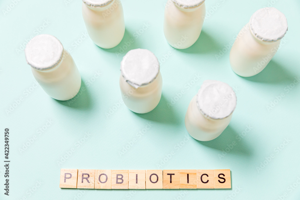 Small bottles with probiotics and prebiotics dairy drink on blue ...