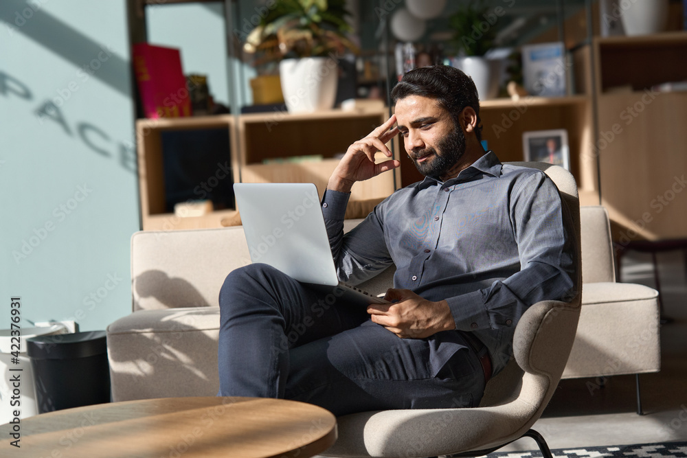 Indian business man executive working on laptop sitting on chair in ...