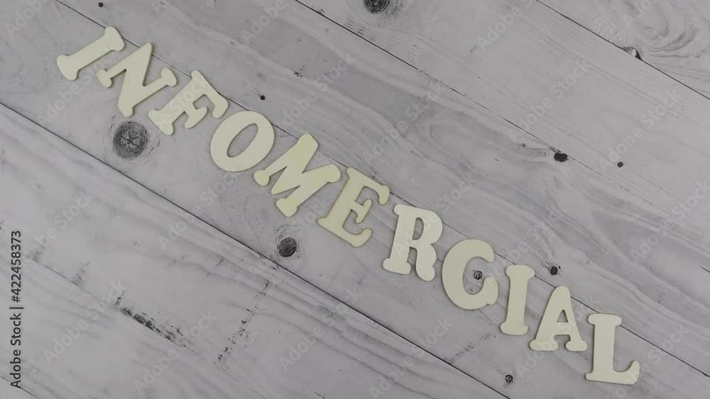Infomercial concept with tilted alphabet letters on light grey wooden ...