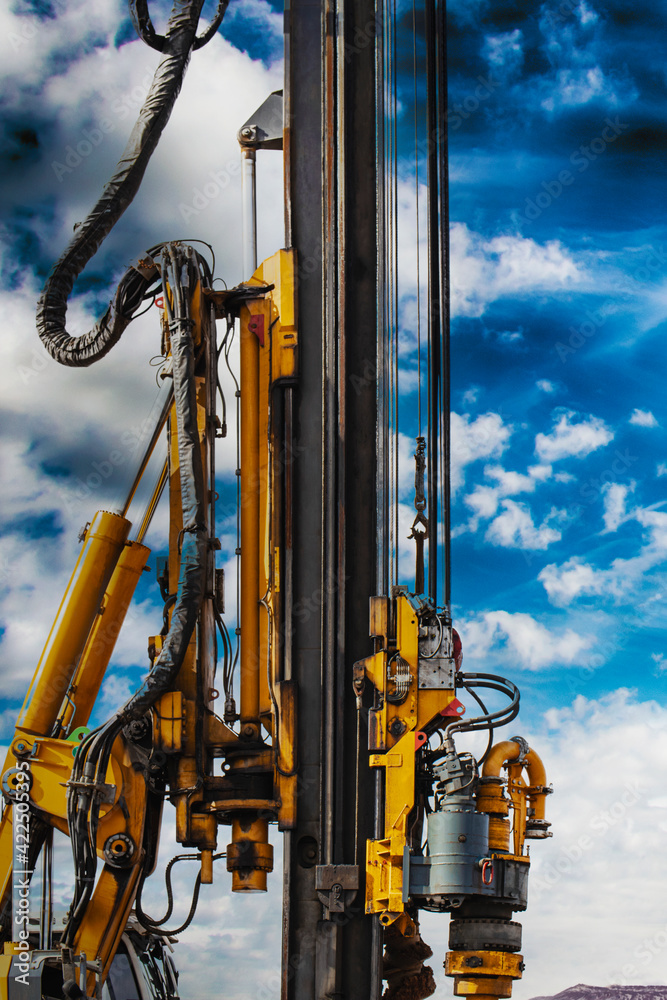 Hydraulic drilling rig against the blue cloudy sky. Vertical image ...