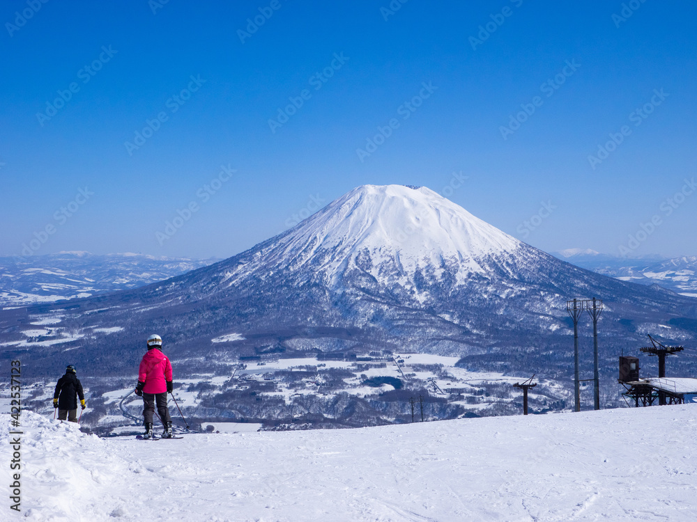 Skiers looking at snowy volcano and town on a clear day in early spring ...