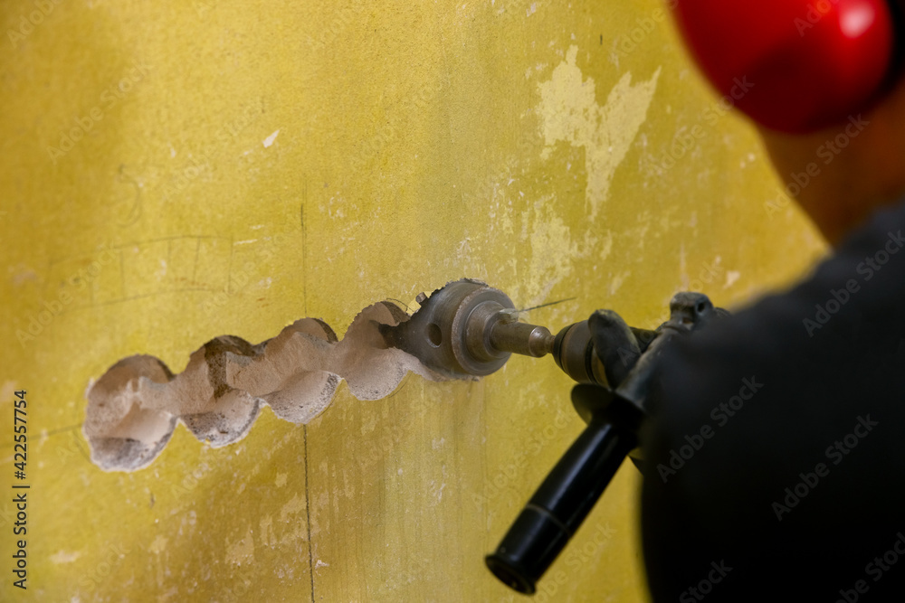 worker drilling hole for electrical socket in concrete brick wall ...