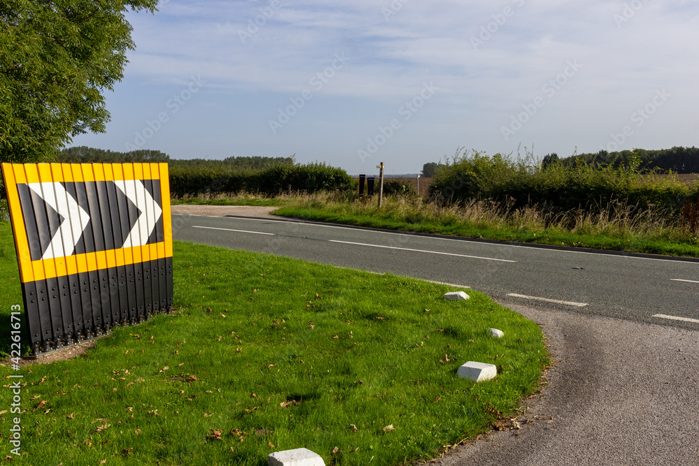Country road junction showing a black, white and yellow road sign ...