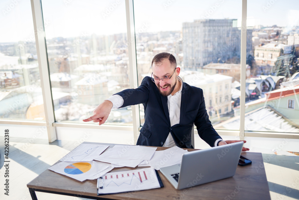 The corporate madman is sitting at the computer in the office and going ...