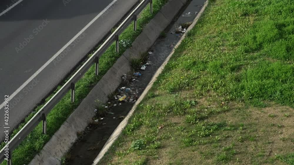 Garbage on the side of the highway. Garbage in the roadside water ...
