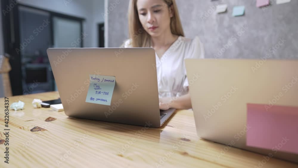 Asian blonde female office worker using laptop computer to gather ...