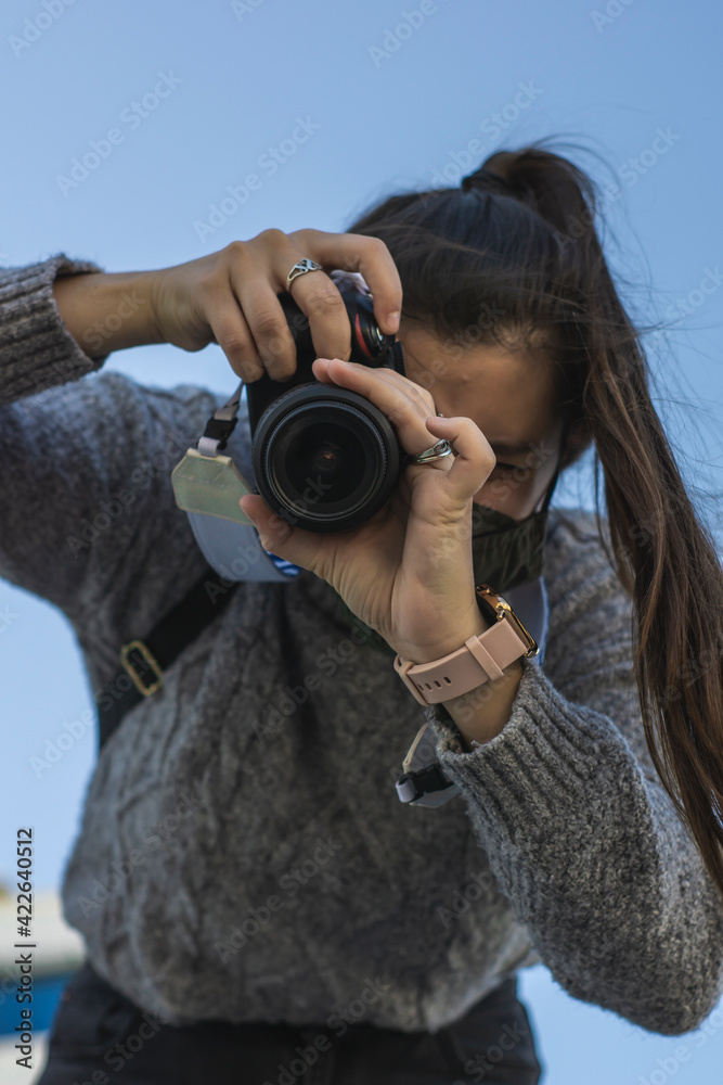 black haired woman taking a photo with reflex camera in portrait format ...